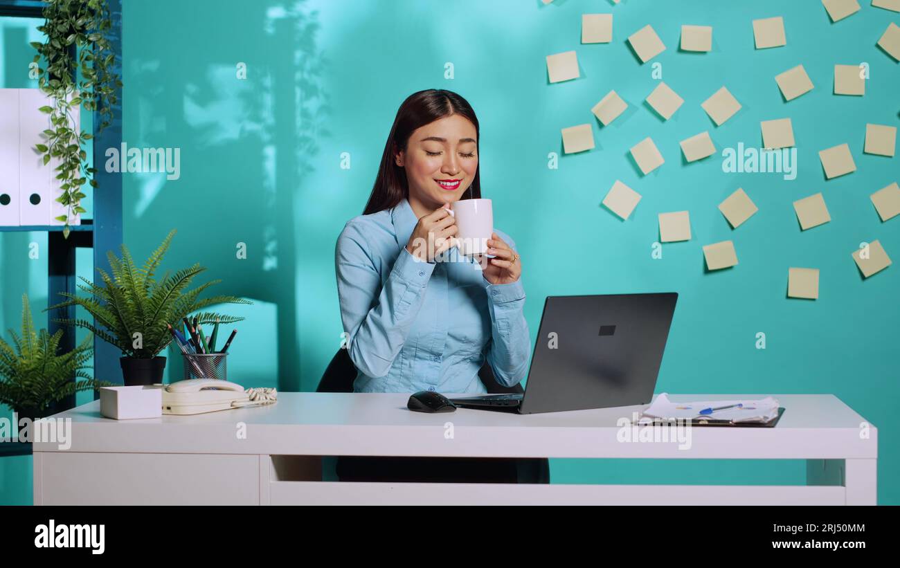Cheerful office clerk savouring cup of coffee, enjoying flavourful ...