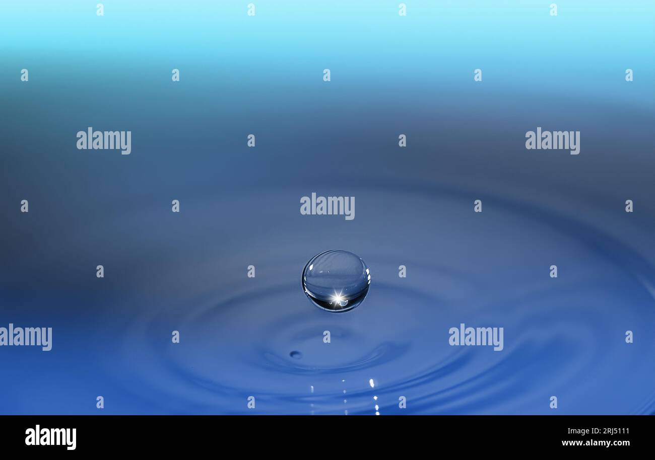 Clear aqua water droplet splashing in concentric circles, capturing ...