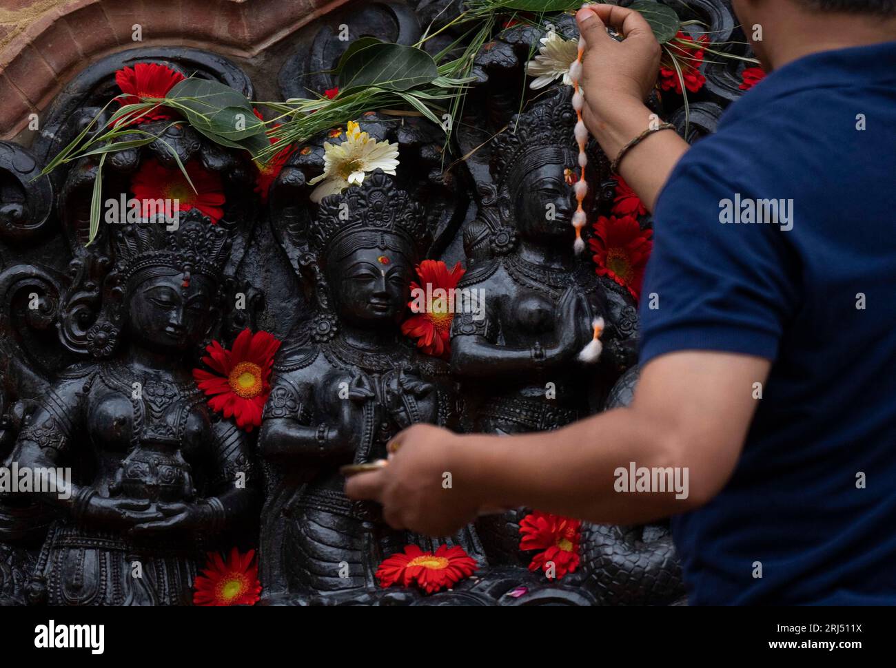 A devotee worships a statue of the serpent god, Naag, on the doorway of ...