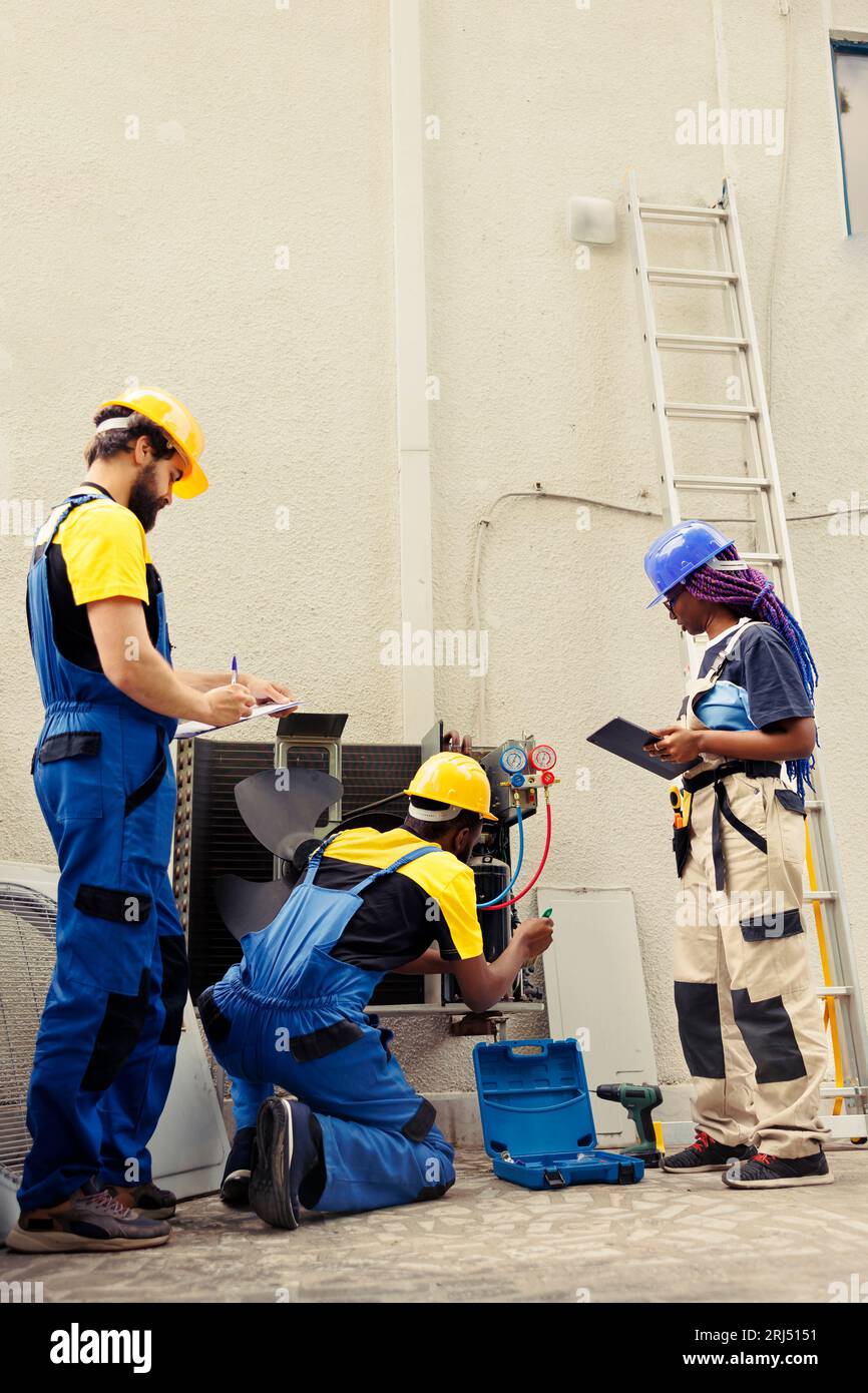 Diverse crew of certified technicians working outside, checking for ...