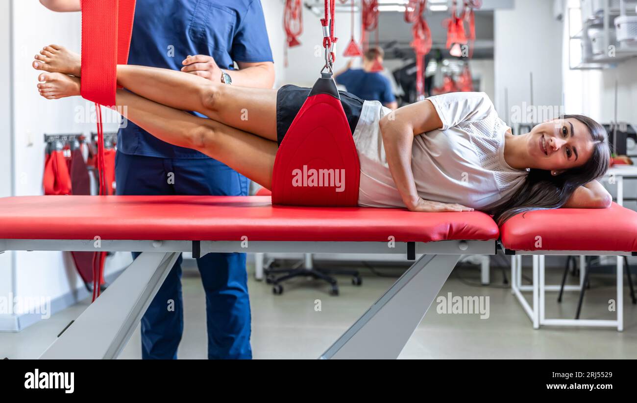 Female patient hanging on suspensions at rehabilitation center Stock ...