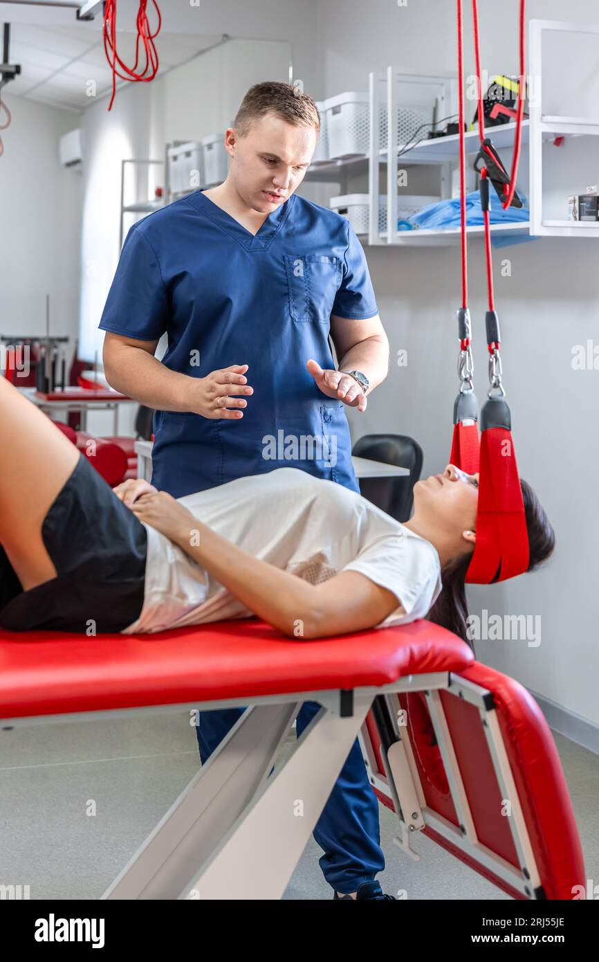 Female patient hanging on suspensions at rehabilitation center Stock ...
