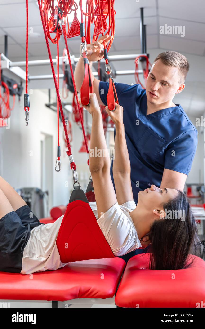 Female patient hanging on suspensions at rehabilitation center Stock ...