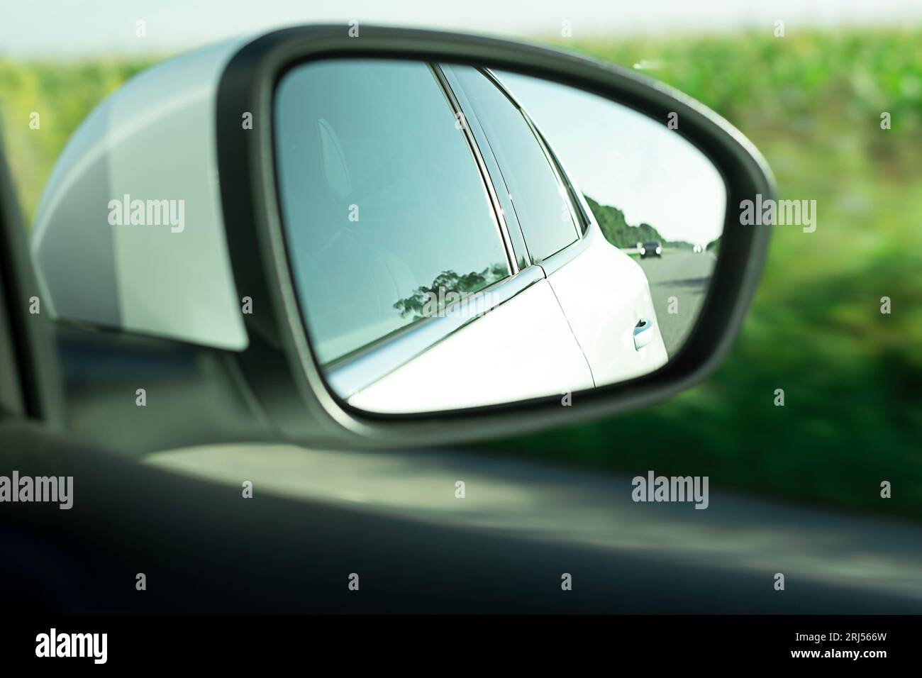 Rear view mirror, close-up, with reflection of a white car when the car ...