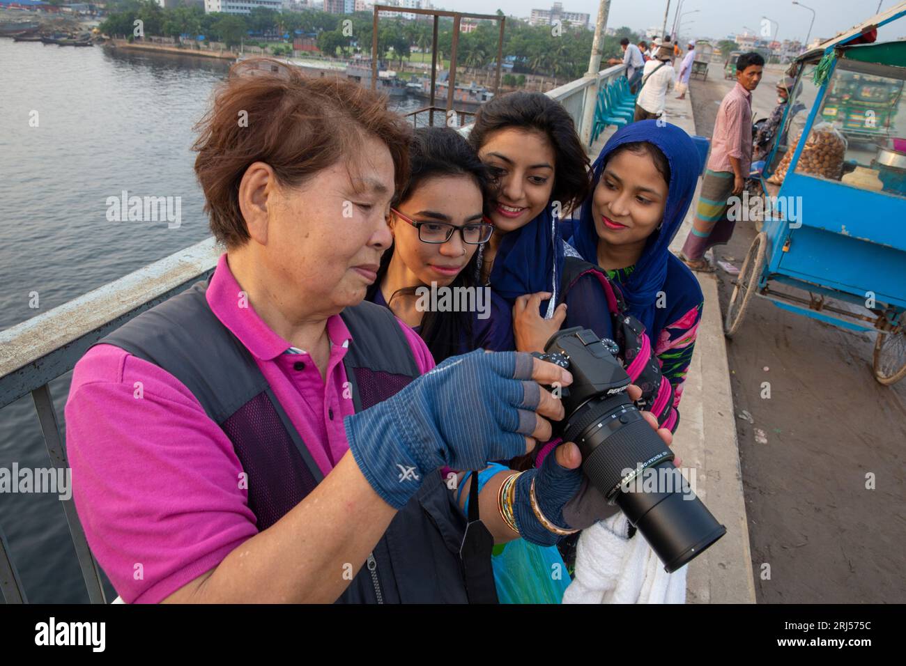 A foreign photographer shows her snaps to some local girls on the Bangladesh-Chaina Friendship ...