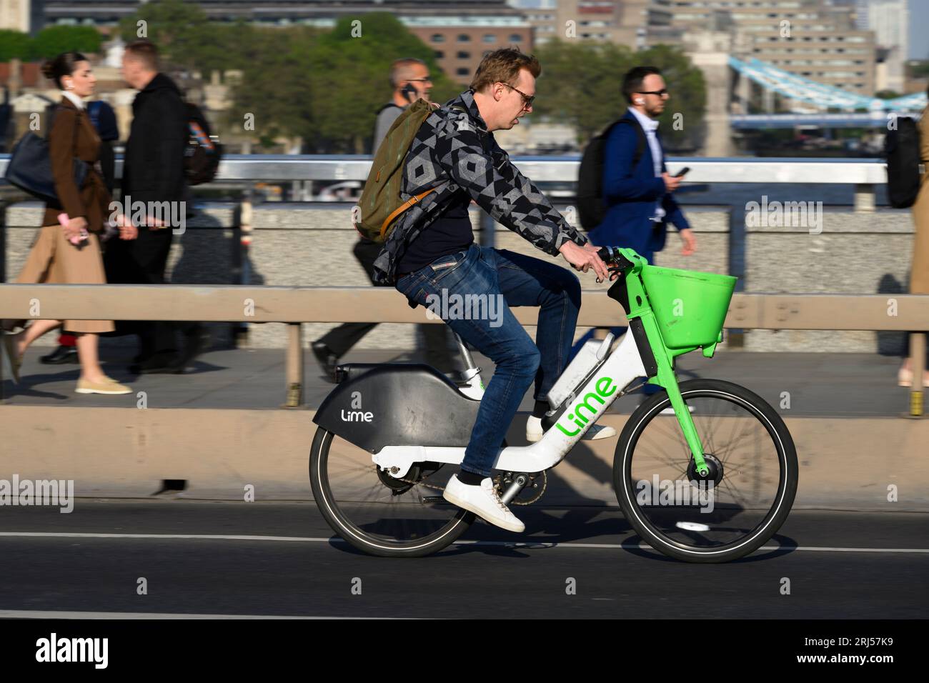 A man commuting on a Lime electric hire bike across London Bridge ...