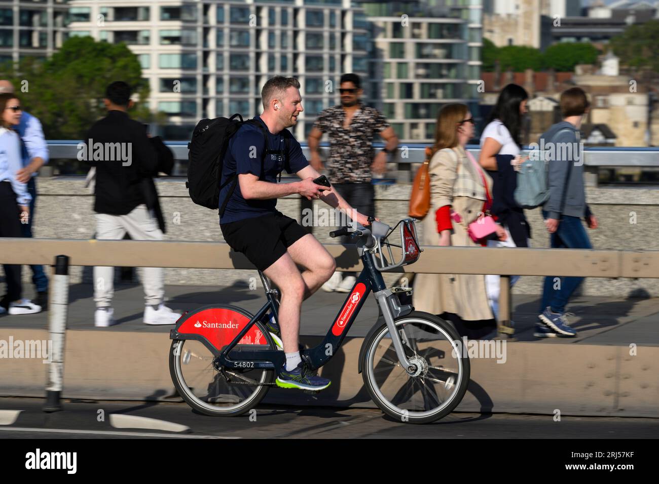 A man cycling across London Bridge, on a Transport for London Santander Cycles hire a bicycle ...