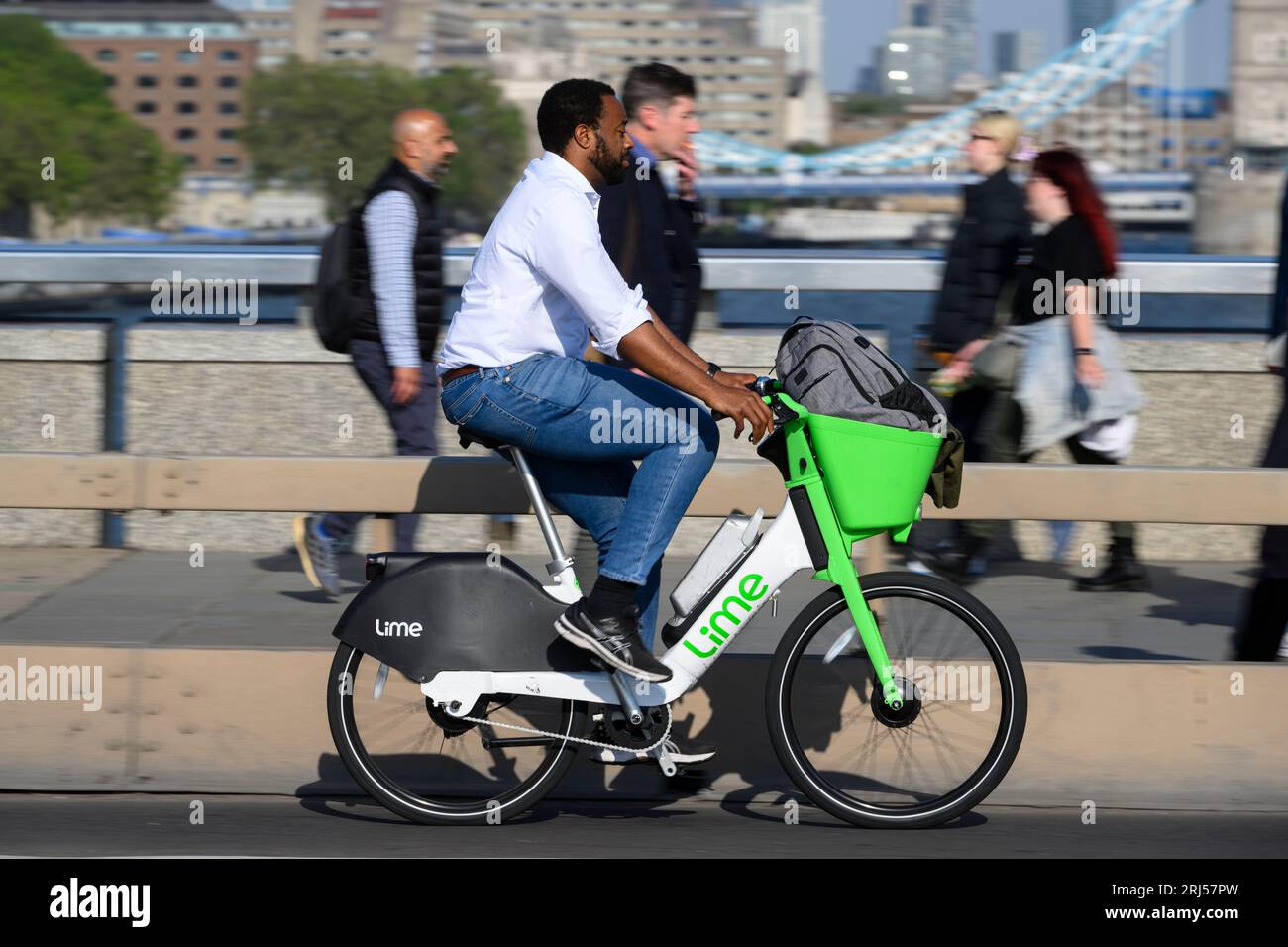 A man commuting on a Lime electric hire bike across London Bridge ...