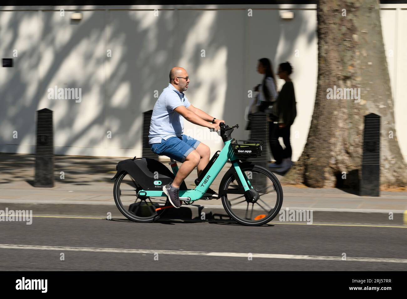 A man cycling a Tier electric hire bicycle along, Whitehall, London, UK ...
