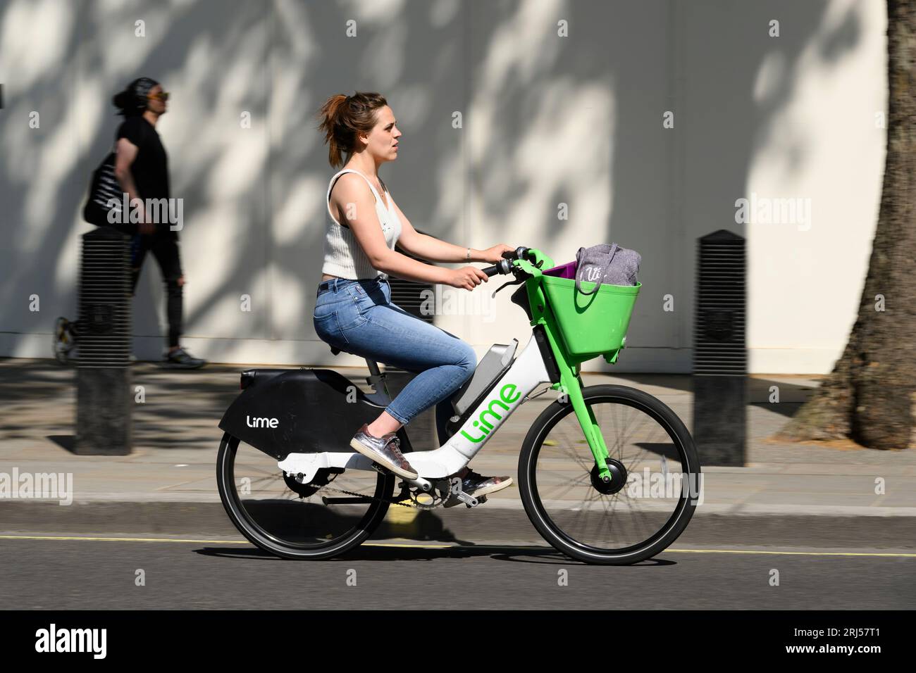 A woman riding a Lime electric hire bike along Whitehall, London, UK. 7 ...