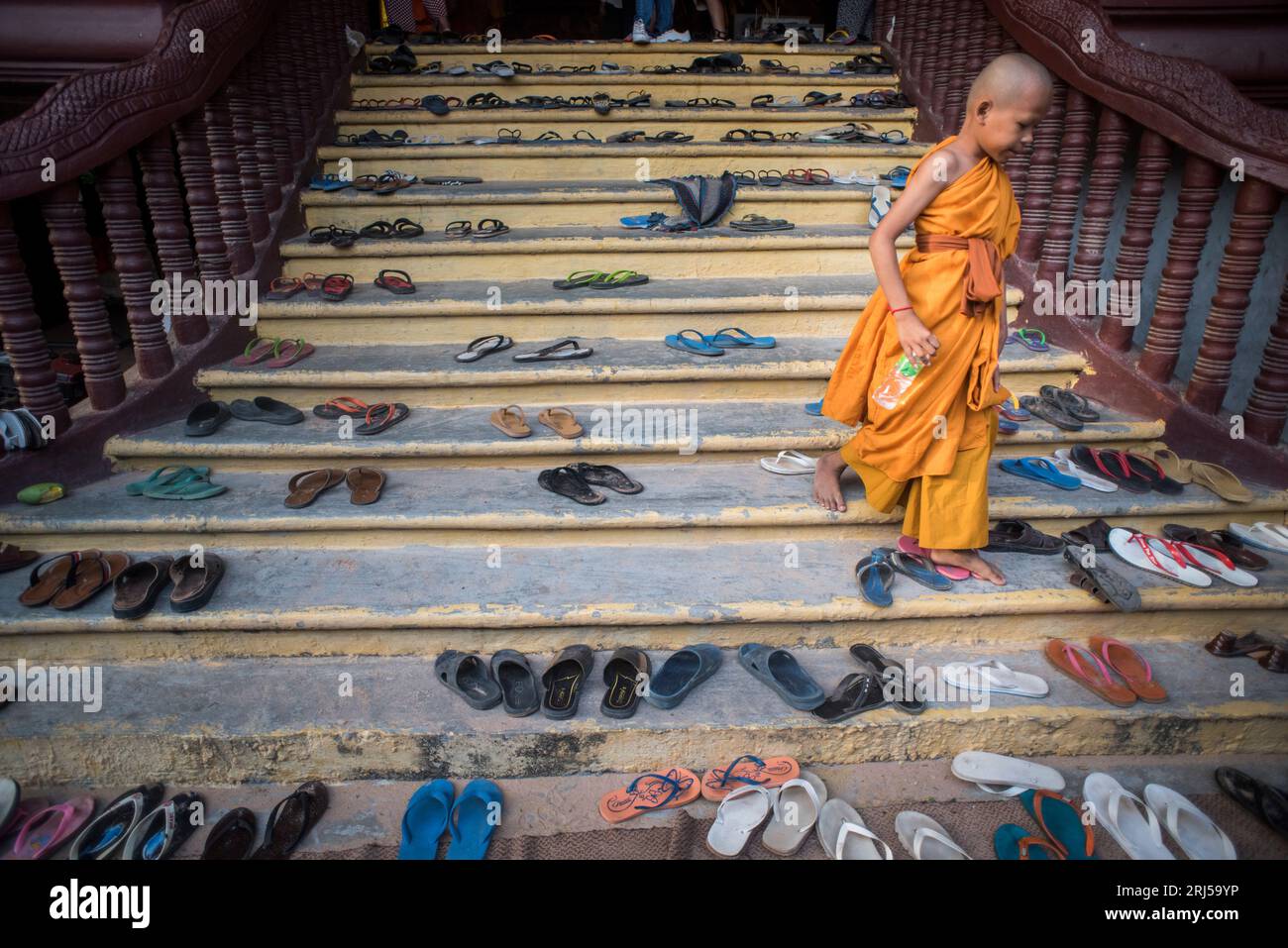 View of a buddhist monk using stairs full of platic sandals, Angkor Wat ...