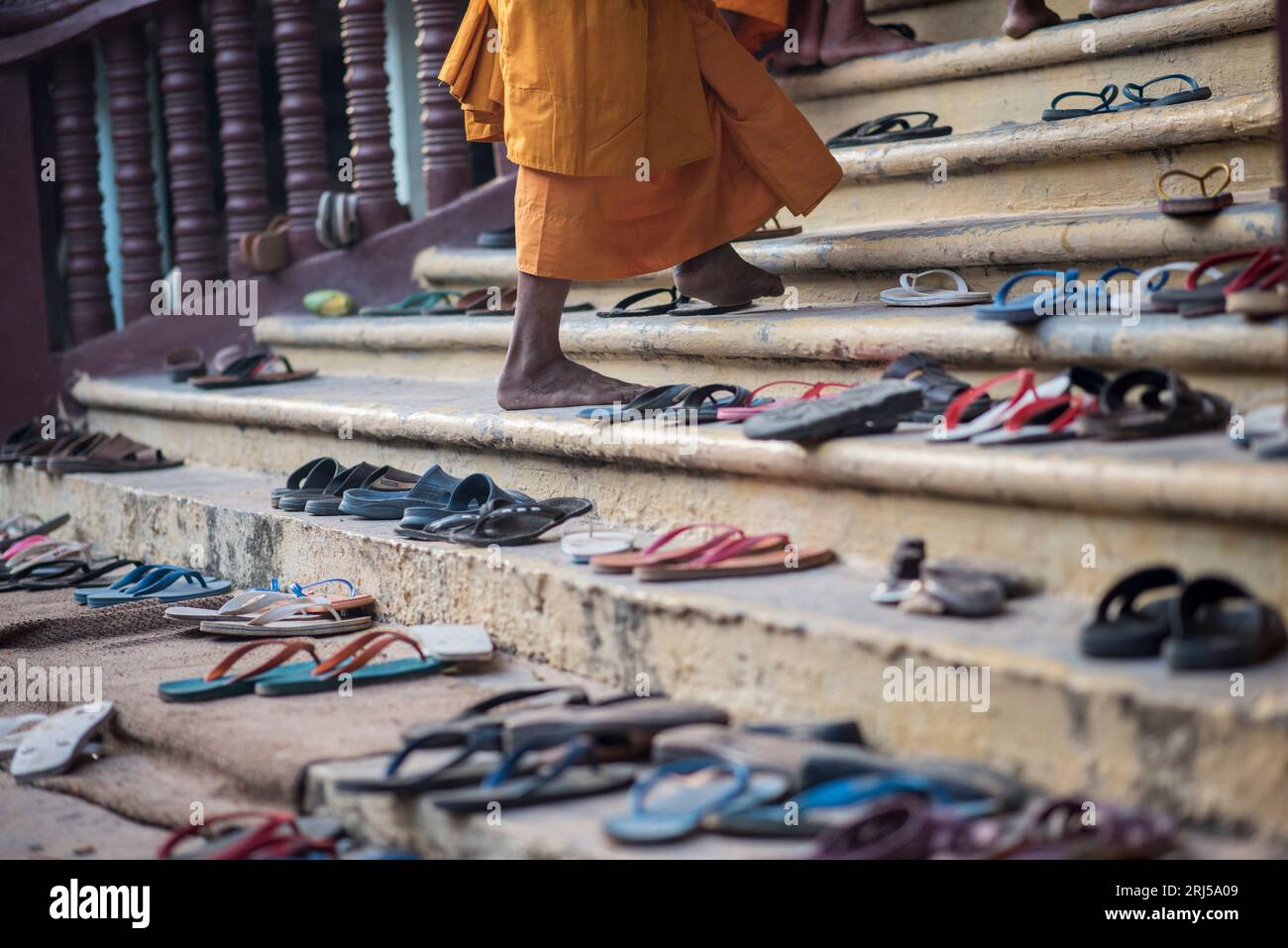 View of a buddhist monk using stairs full of platic sandals, Angkor Wat ...