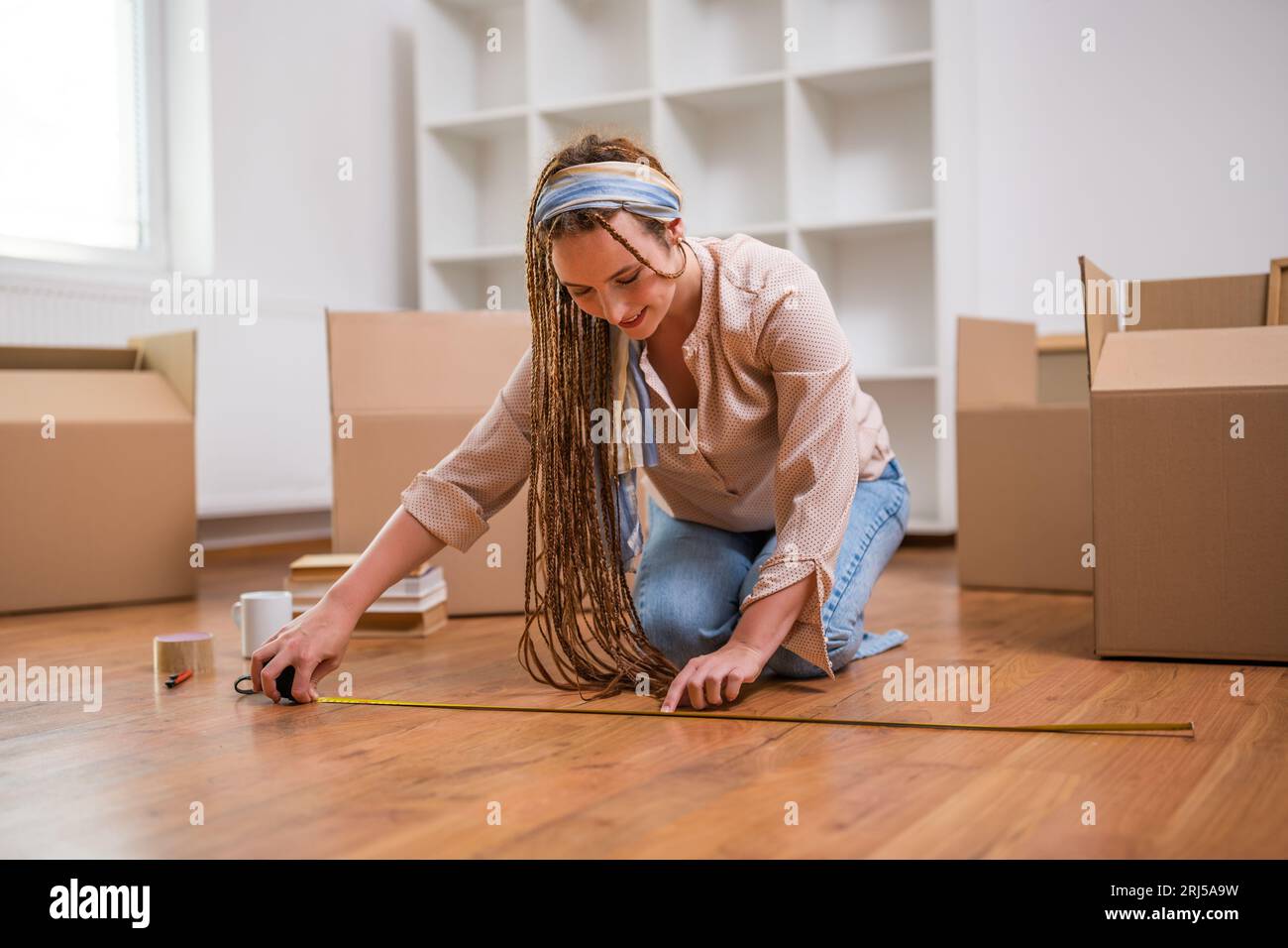 Modern ginger woman with braids moving into new home and measuring ...