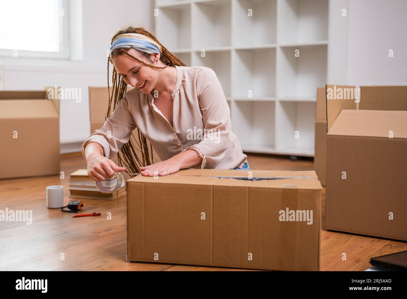 Modern ginger woman with braids moving into new home Stock Photo - Alamy