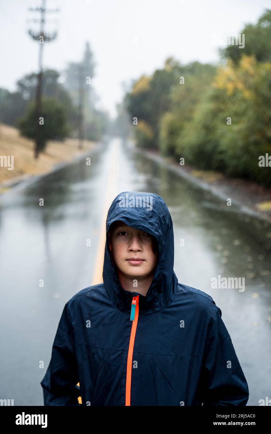 Teenage boy standing in middle of the road during rainstorm Stock Photo ...