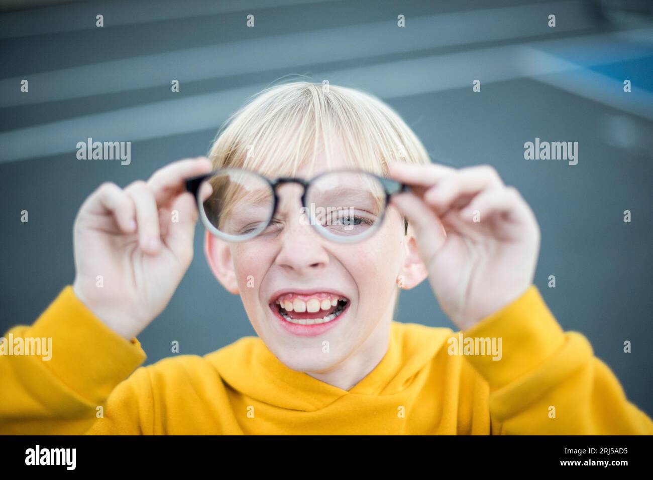 Young teenage boy playing with eyeglasses in front of his face Stock ...