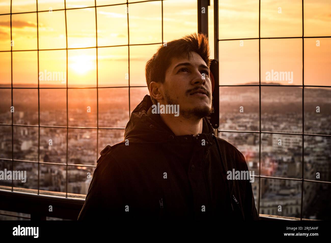 A young men in the top of the Eiffel Tower looking the sky Stock Photo ...