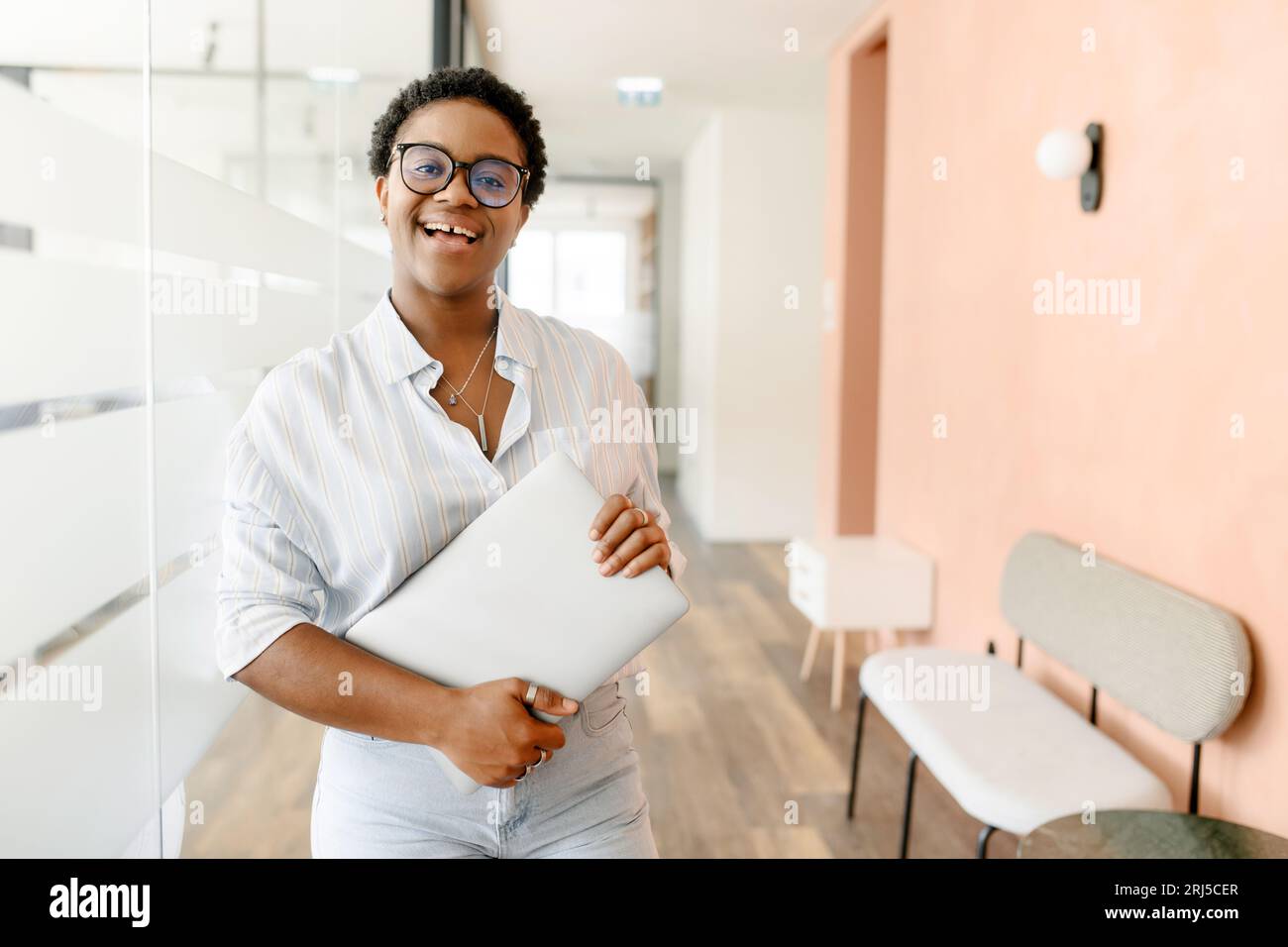 Cheerful inspired african female employee standing in modern office ...