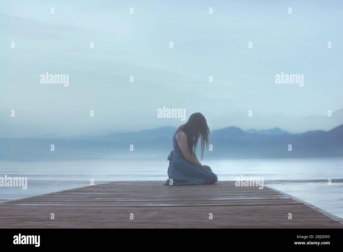 lonely woman kneeling on a pier on the sea lets herself be carried away ...