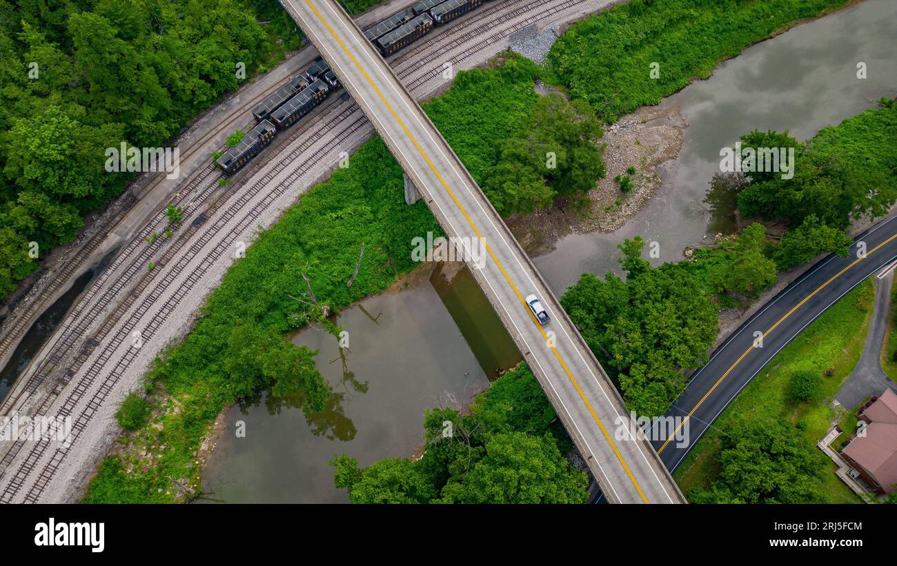An aerial view of a road bridge over a narrow river surrounded by ...