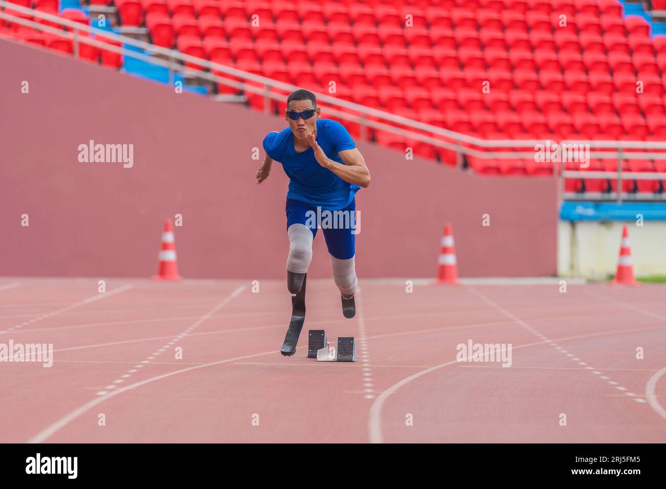 An Asian paralympic athlete equipped with prosthetic running blades training in a sports stadium ...