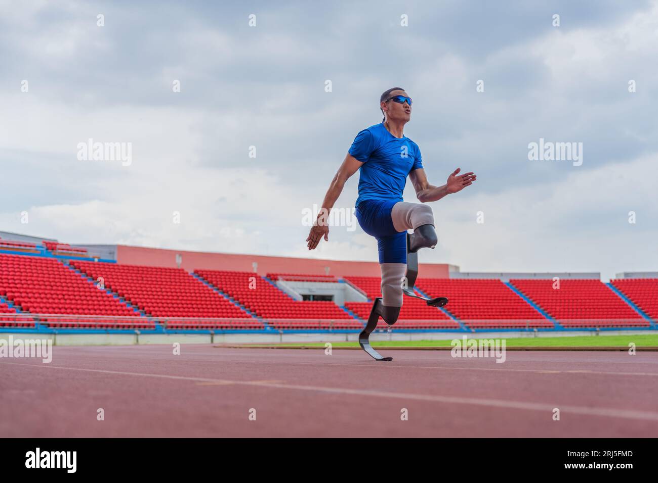 An Asian paralympic athlete equipped with prosthetic running blades training in a sports stadium ...