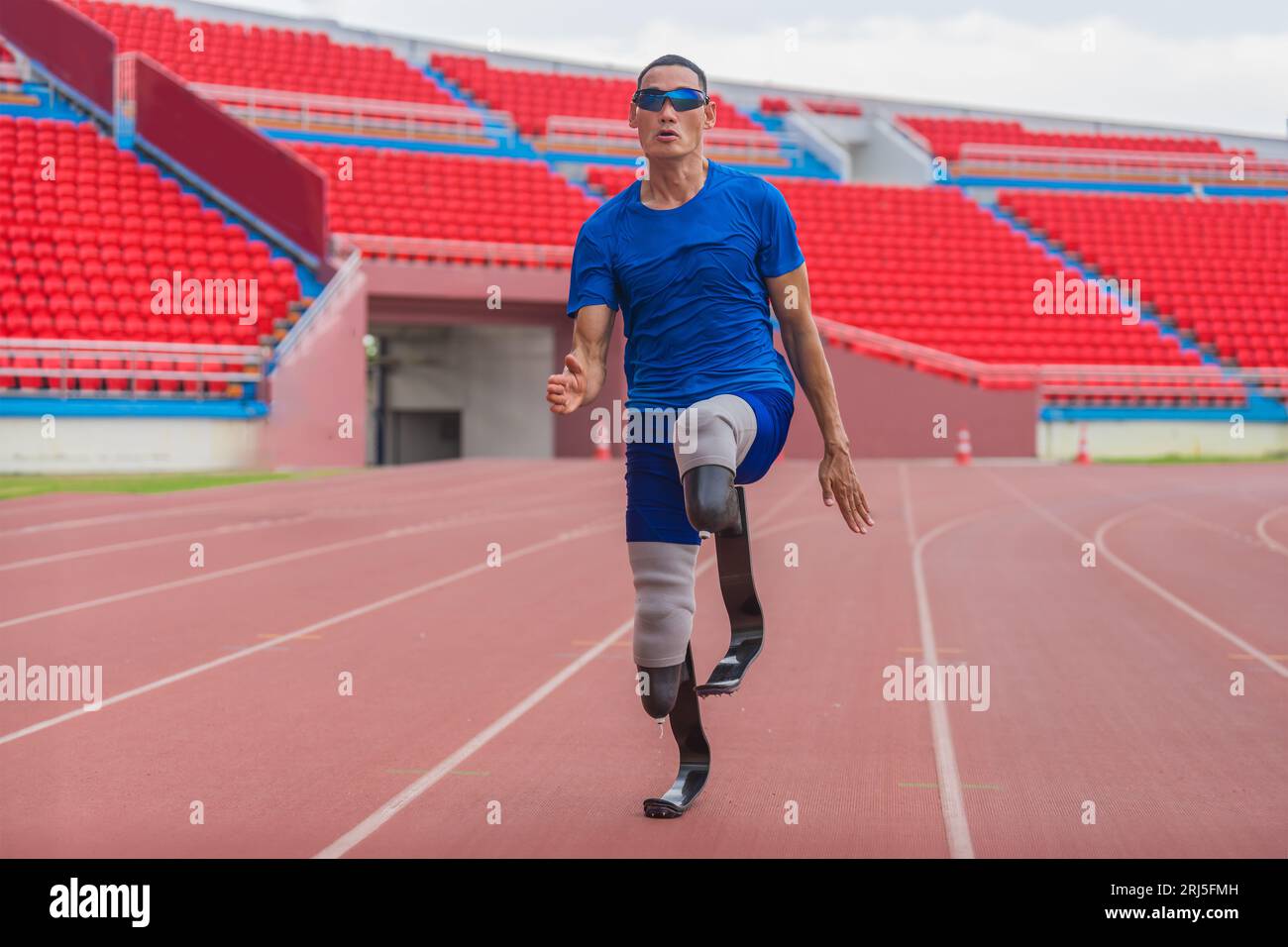 An Asian paralympic athlete equipped with prosthetic running blades training in a sports stadium ...
