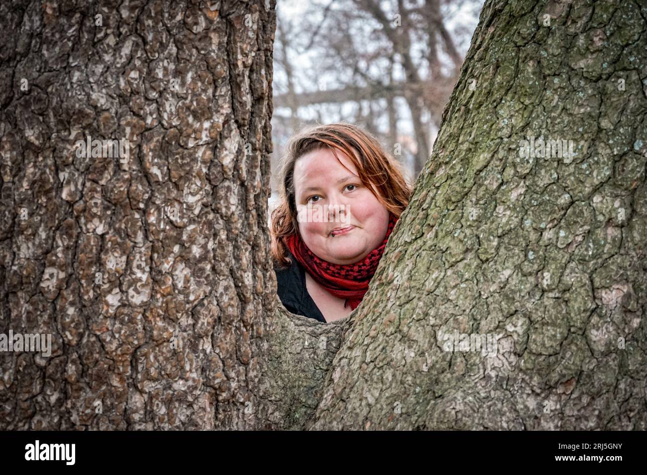 Portrait of smiling girl hiding behind tree trunk Stock Photo - Alamy