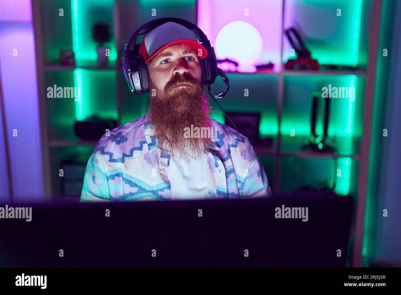 Young redhead man streamer playing video game using computer at gaming ...