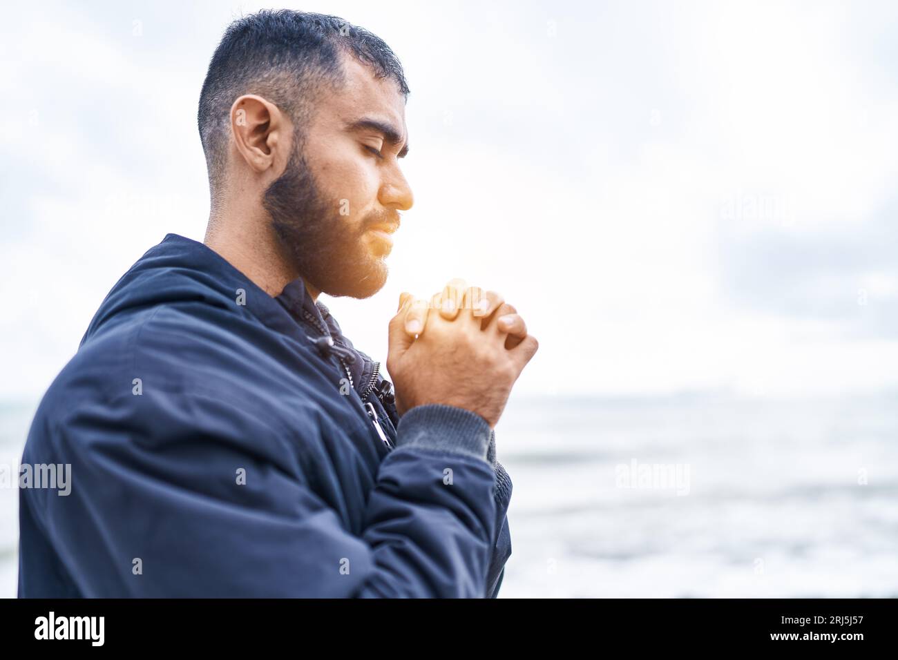 Young hispanic man praying with closed eyes at seaside Stock Photo - Alamy