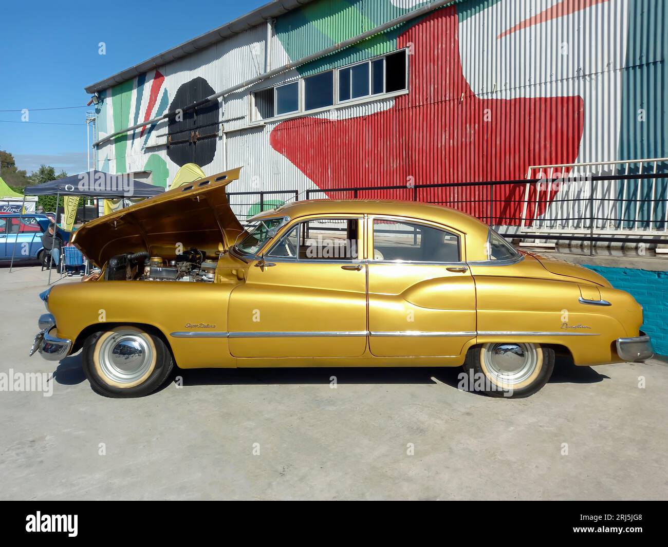 Old golden 1950 Buick Super Deluxe Dynaflow sedan street. Open hood showing engine. Side view ...