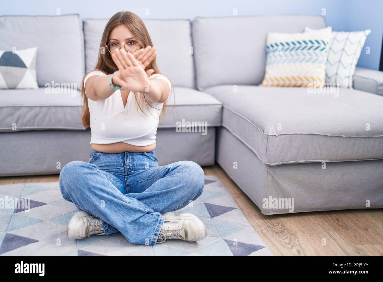 Young caucasian woman sitting on the floor at the living room rejection ...