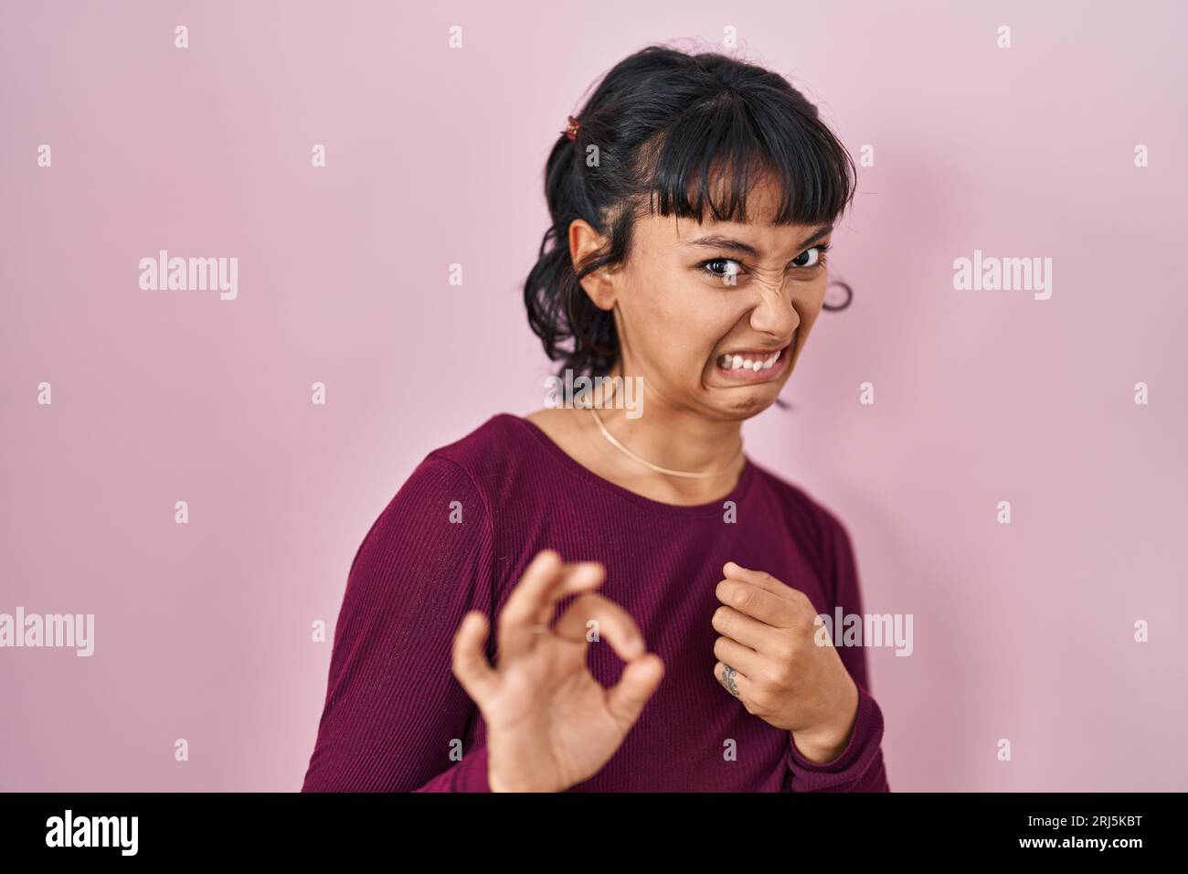 Young beautiful woman standing over pink background disgusted ...