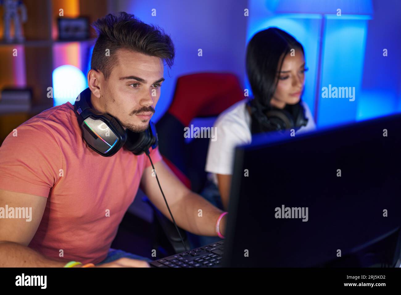 Man and woman streamers playing video game using computer at gaming ...