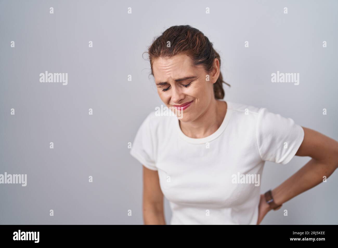 Beautiful brunette woman standing over isolated background suffering of ...