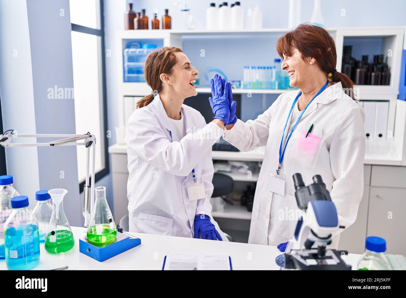 Two women scientist smiling confident high five with hands raised up at ...