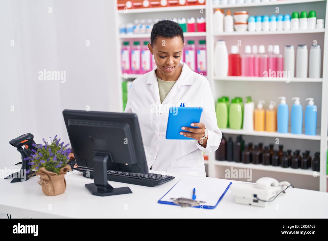 African american woman pharmacist using computer and touchpad at ...
