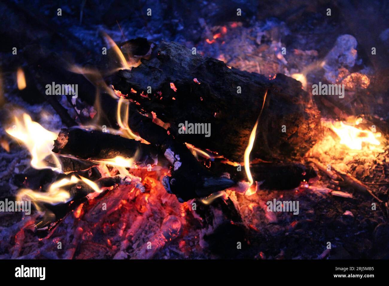 An outdoor scene with a bonfire illuminated by vibrant red flames Stock ...
