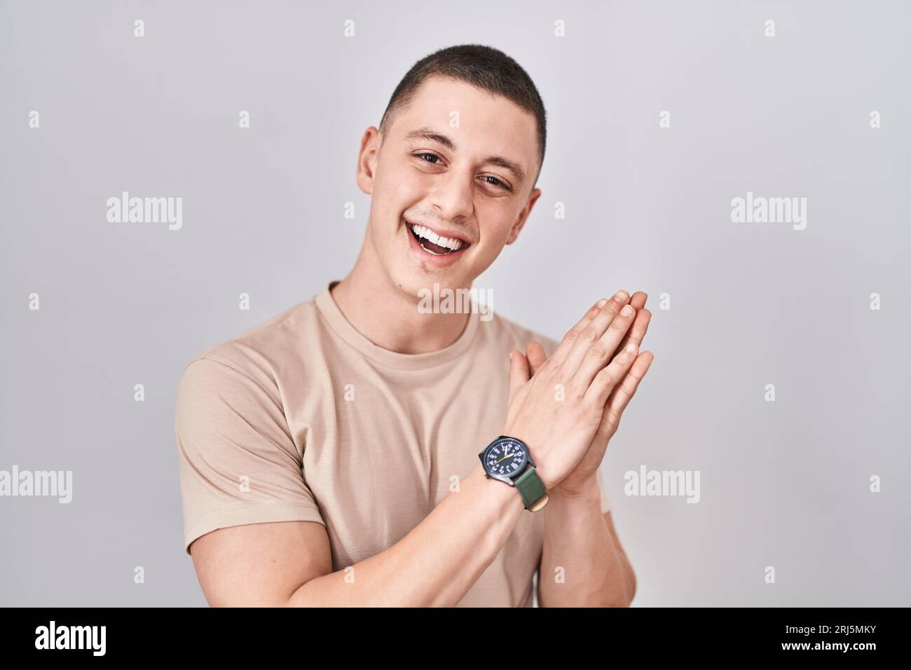 Young man standing over isolated background clapping and applauding ...
