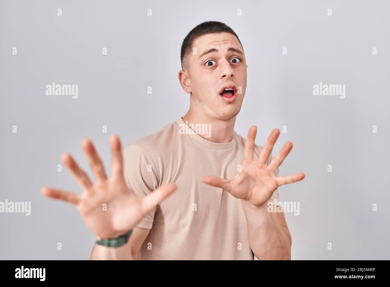 Young man standing over isolated background afraid and terrified with ...
