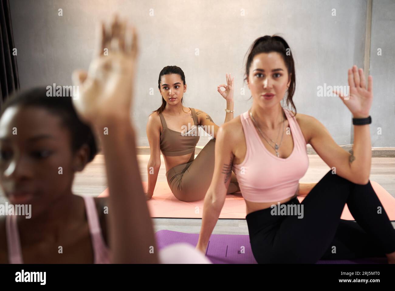 Group of women doing half spinal twist pose when doing yoga together ...
