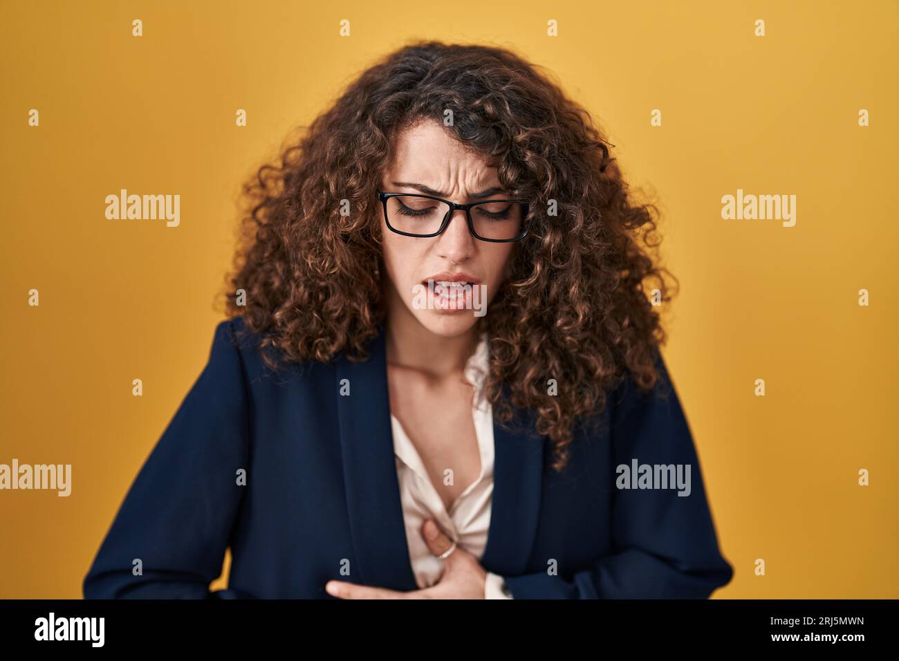 Hispanic woman with curly hair standing over yellow background with ...