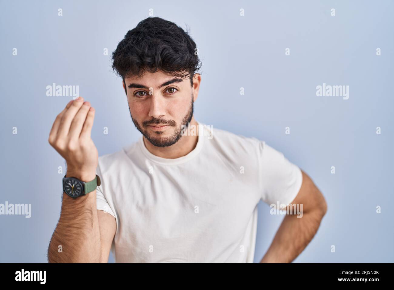 Hispanic man with beard standing over white background doing italian ...