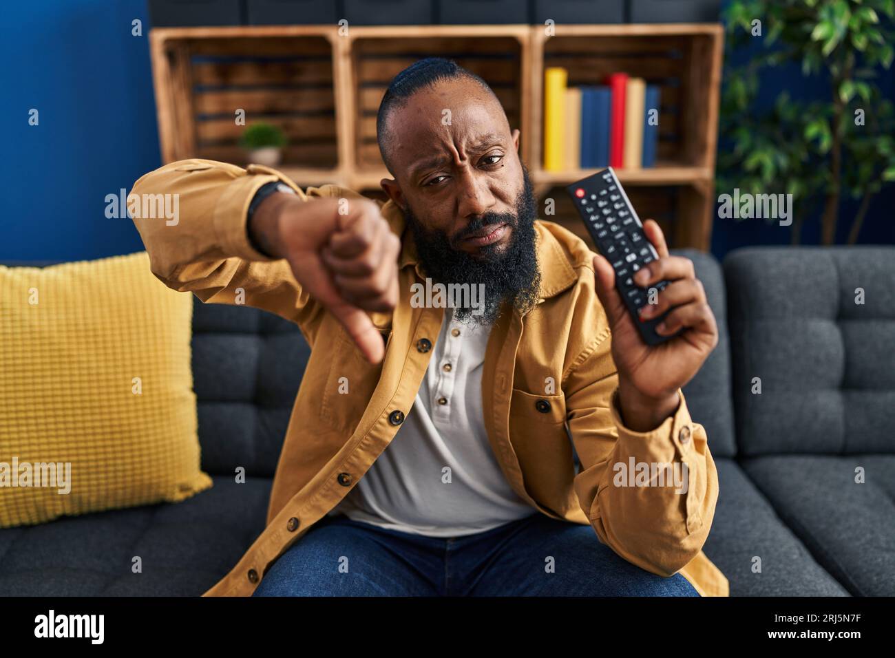 African american man holding television remote control with angry face ...