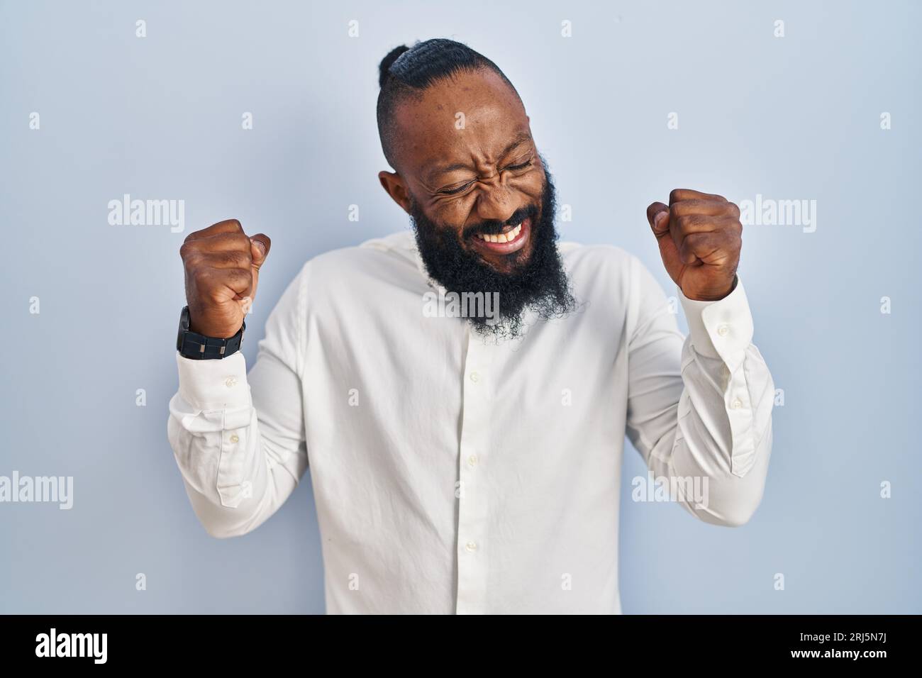 African american man standing over blue background excited for success ...