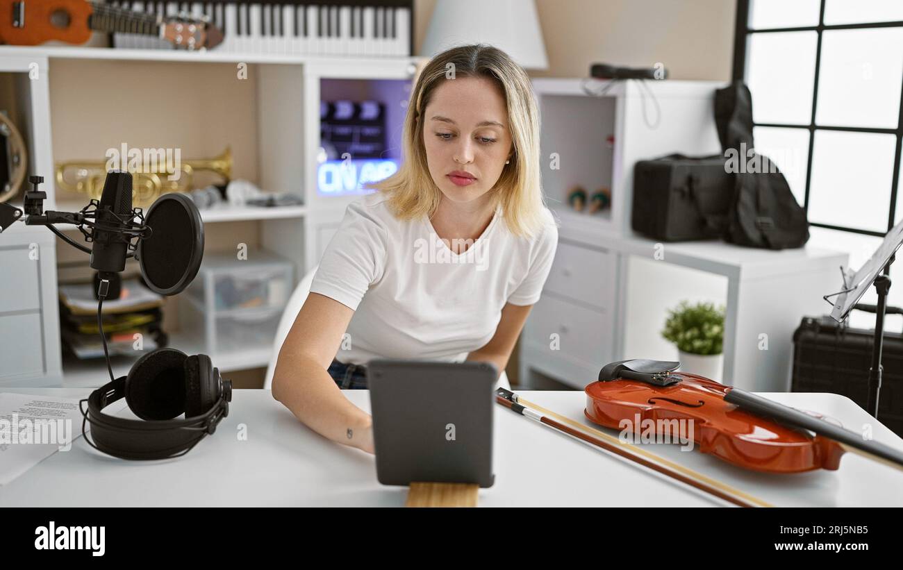 Young blonde woman musician using touchpad at music studio Stock Photo ...