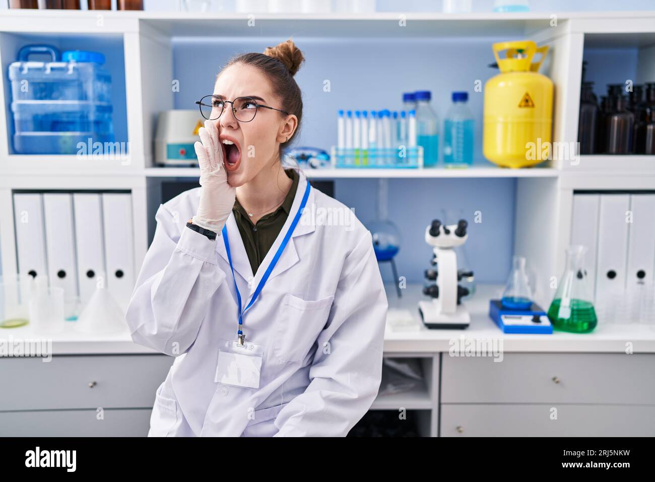 Young hispanic girl working at scientist laboratory clueless and ...