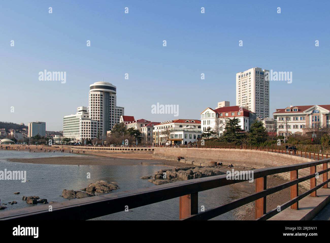 A scenic view of the seaside boardwalk against buildings at Qingdao ...