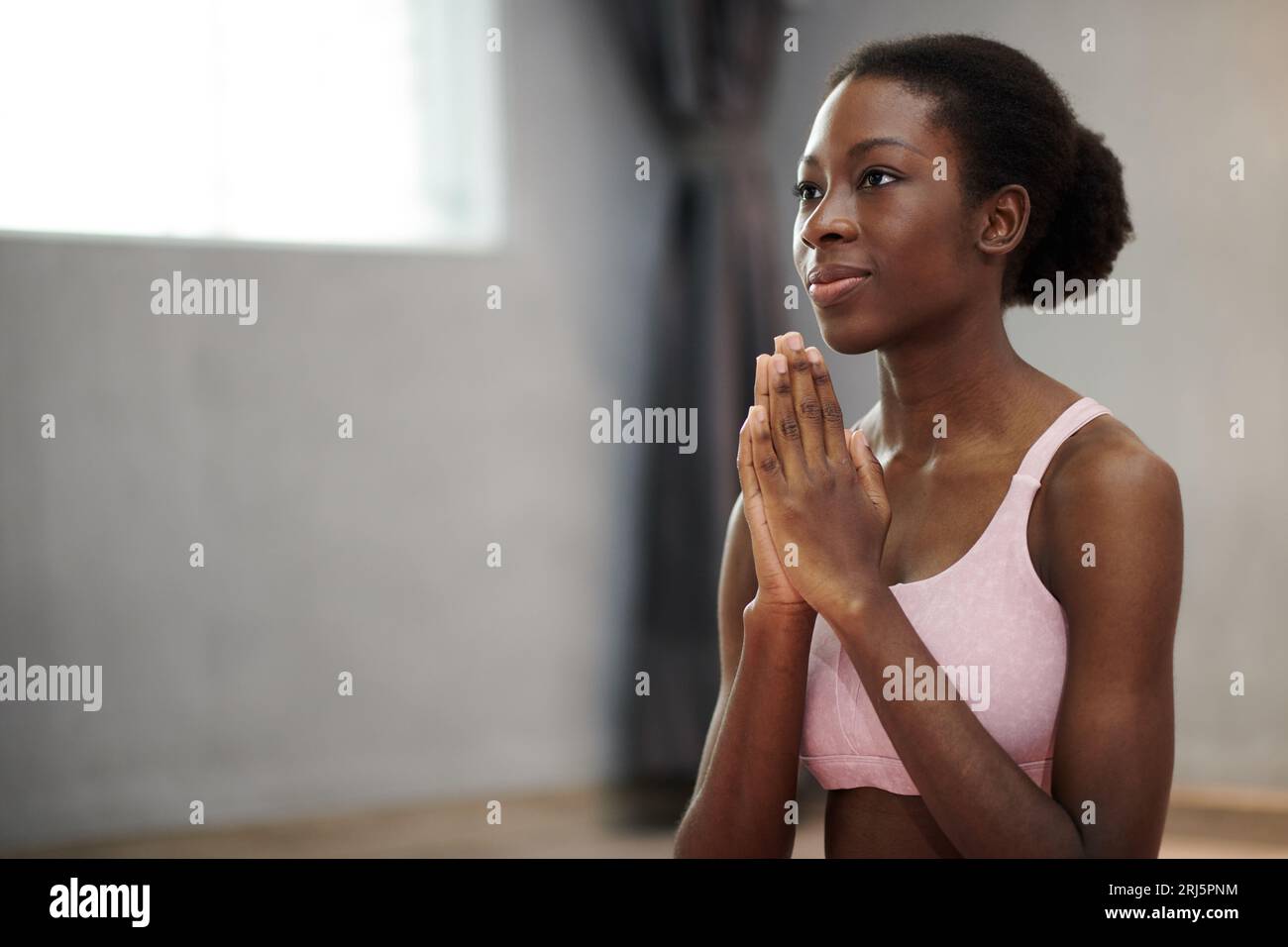 Portrait of smiling young yogi keeping hands in namaste mudra and ...