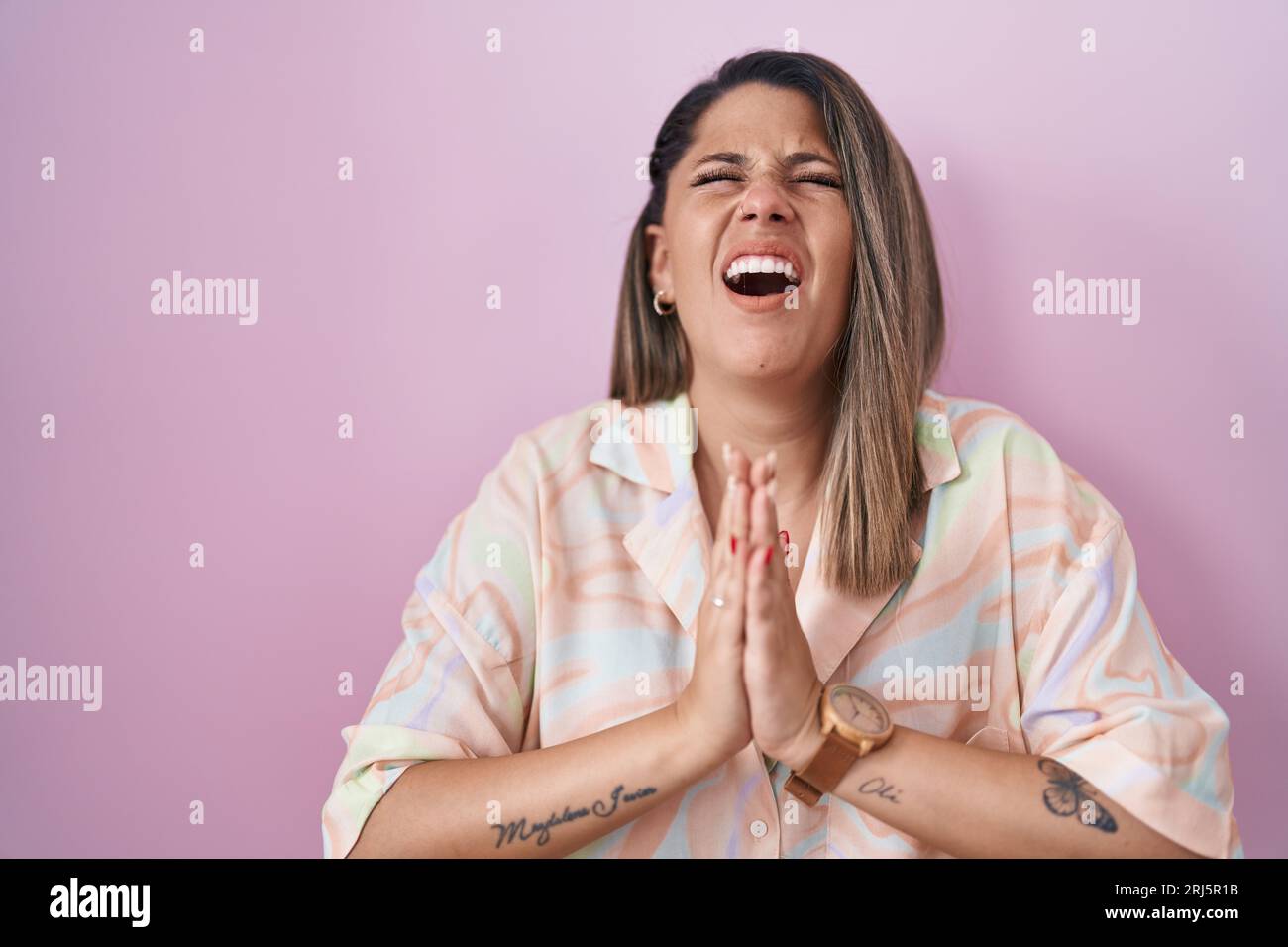 Blonde woman standing over pink background begging and praying with ...